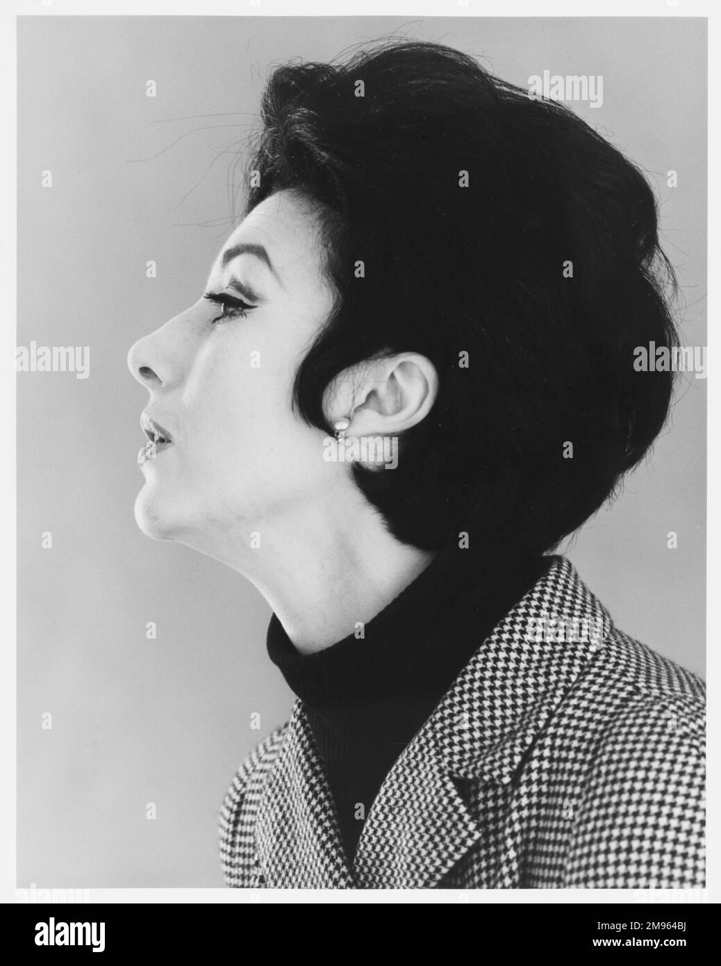 Head and shoulders portrait of a dark haired woman putting her nose up ...