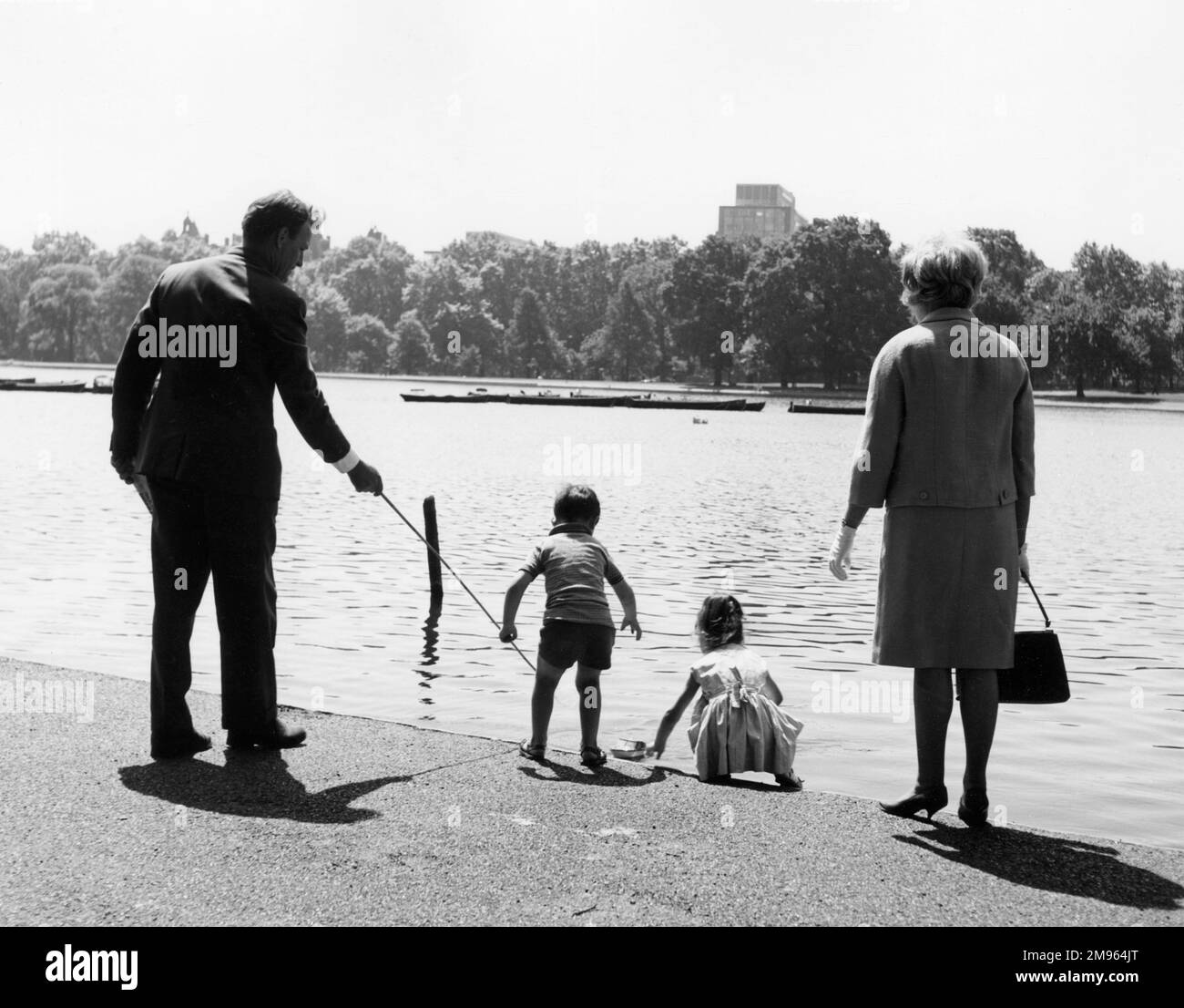 A little boy and his sister try to sail a toy boat on the Serpentine ...