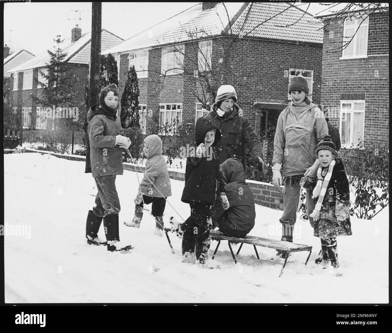 Mothers and children playing with a sledge in the snow on a suburban ...