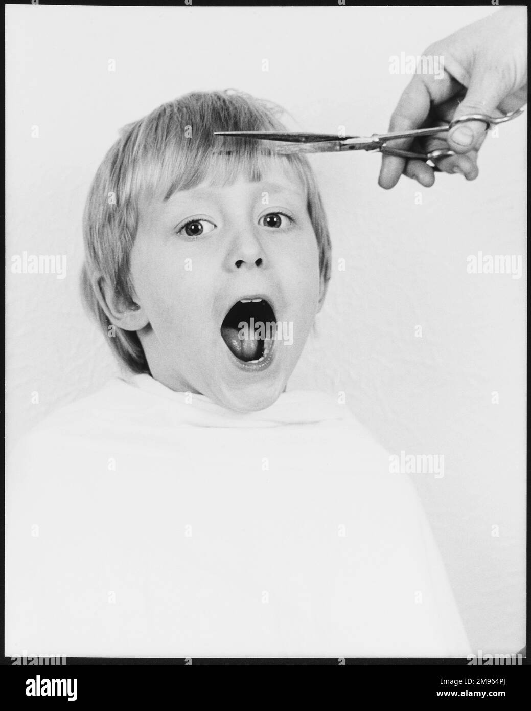 A boy squeals as a pair of scissors is applied to his fringe - the ...
