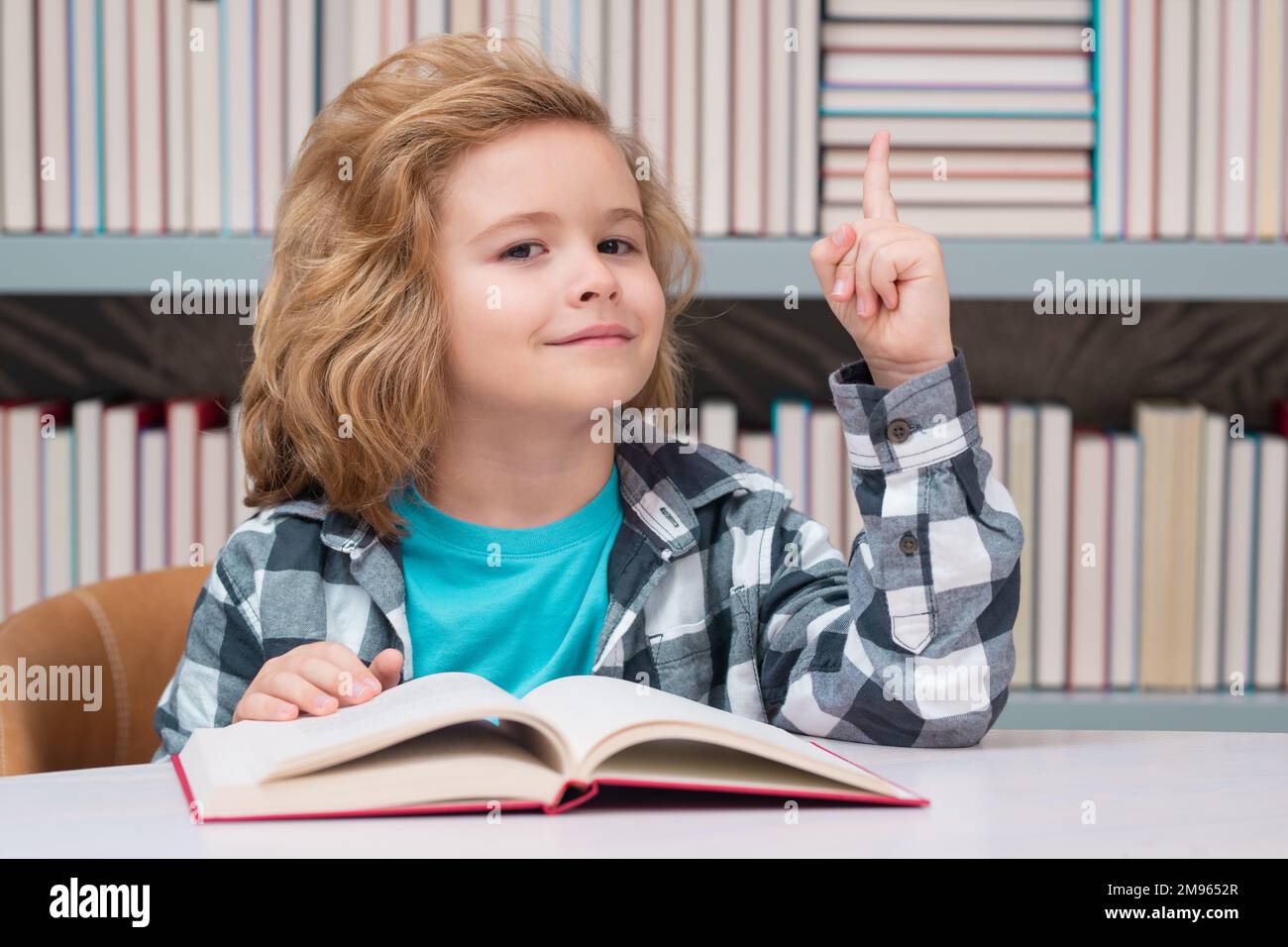 Child reading a book in a school library. School boy education concept ...
