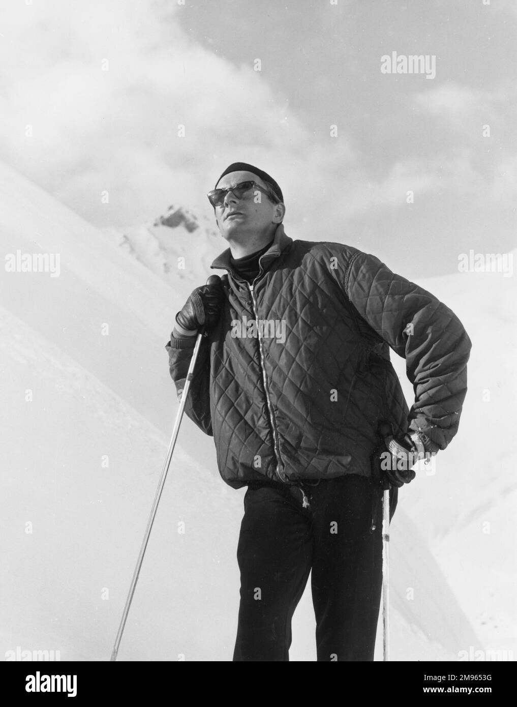 A male skier wearing a quilted jacket poses on the slopes Stock Photo ...