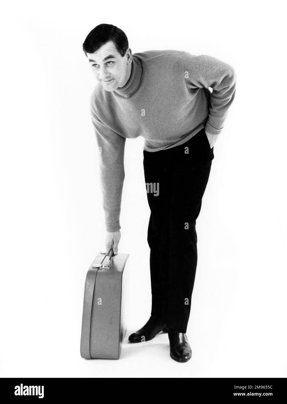 A man picks up his suitcase Stock Photo - Alamy