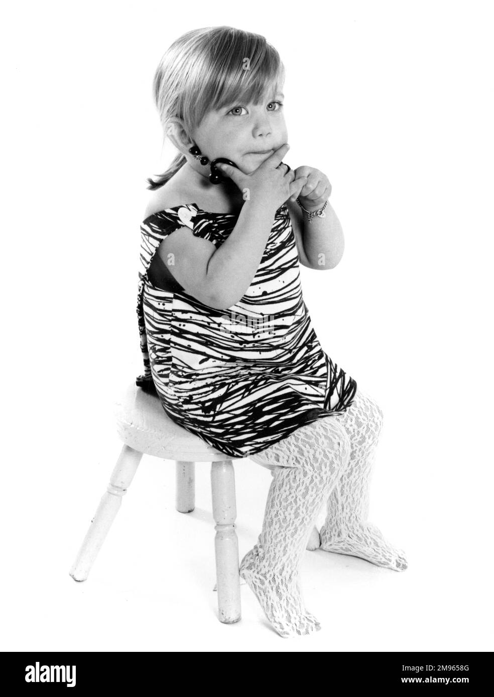 A little girl sitting on a stool Stock Photo - Alamy