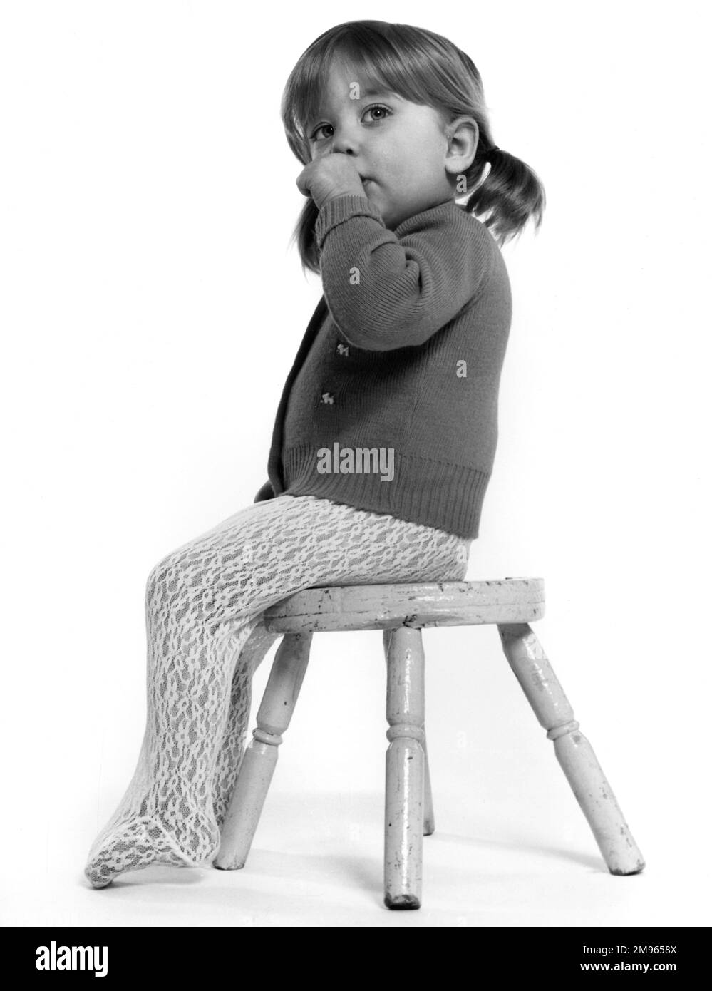 A little girl sitting on a stool Stock Photo - Alamy