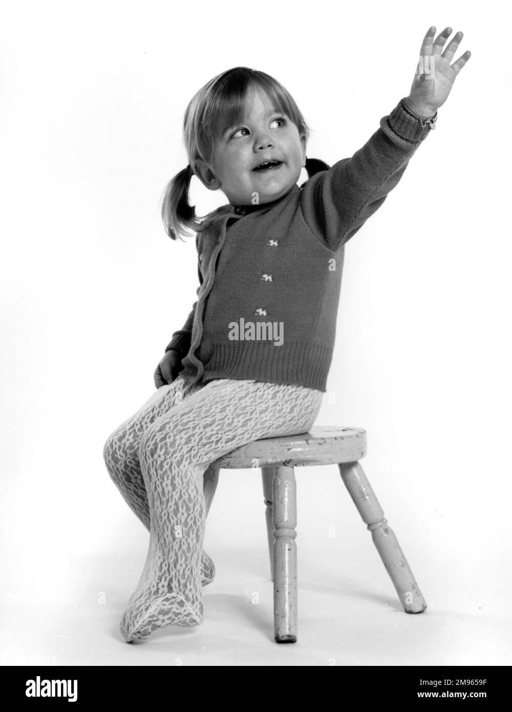 A little girl sitting on a stool Stock Photo - Alamy