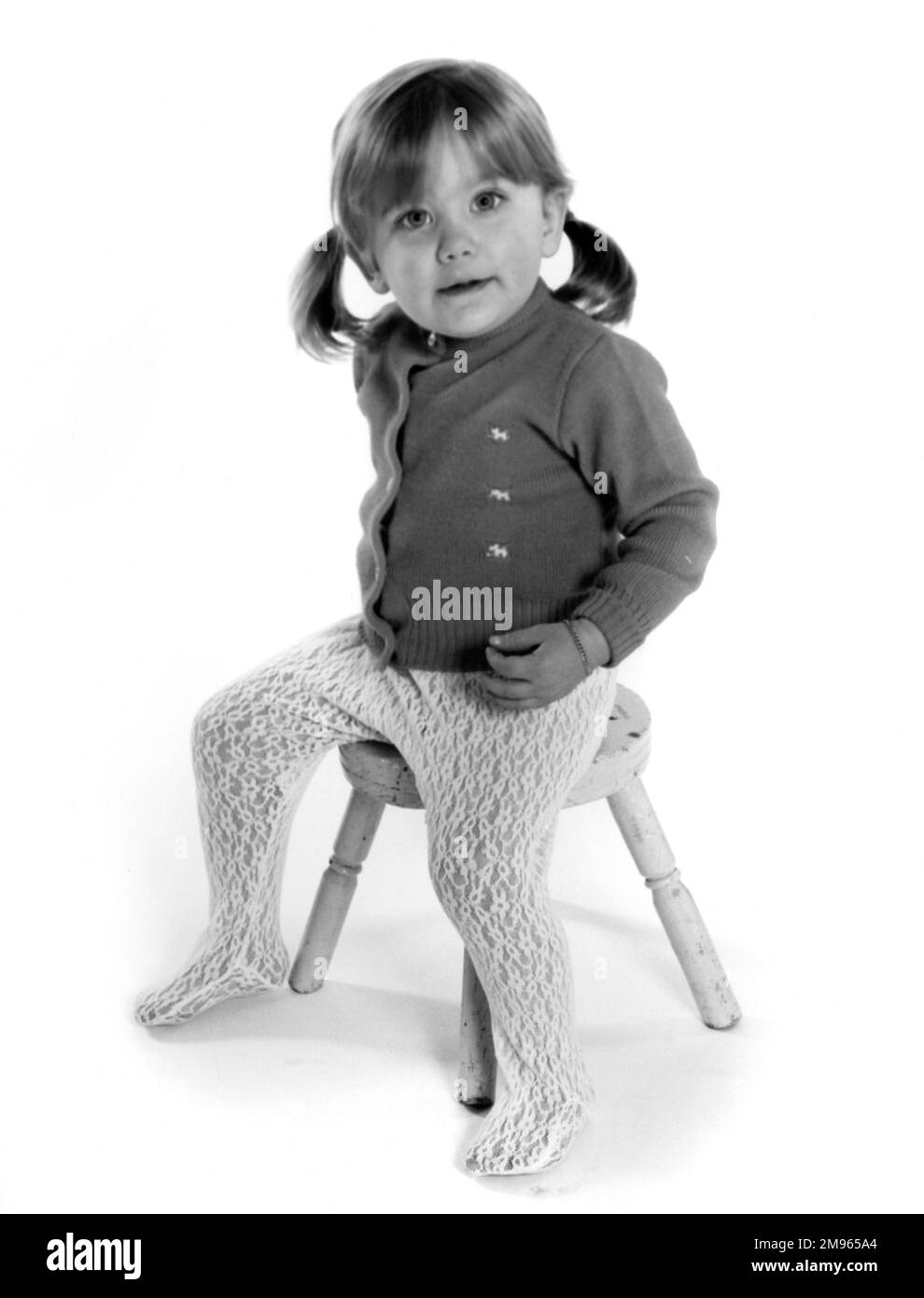 A little girl sitting on a stool Stock Photo - Alamy