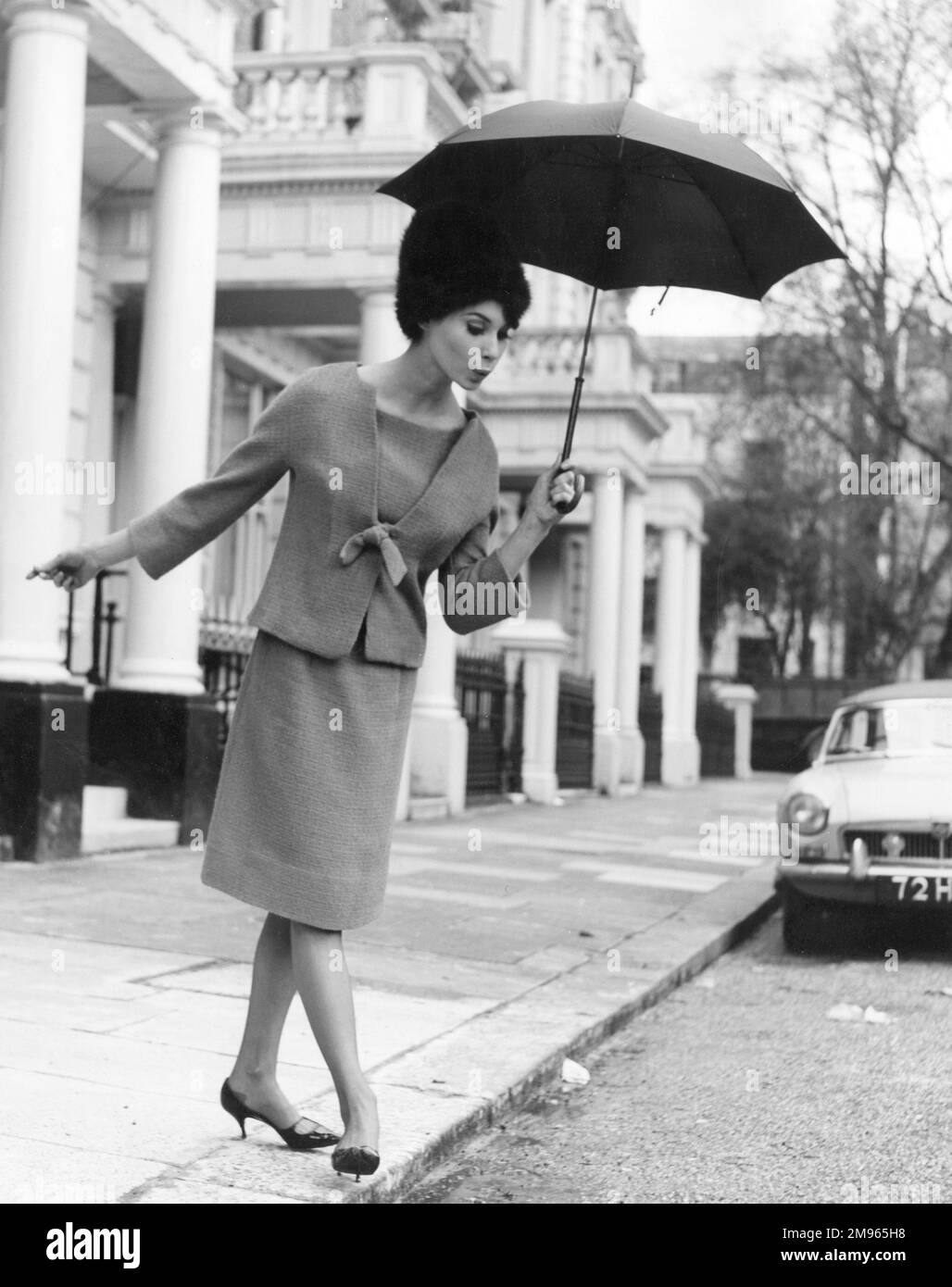 A smart young woman who can step off a pavement and hold an umbrella ...