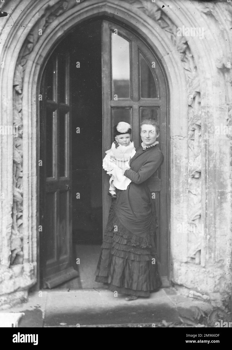 A mother stands on the step in the half- open doorway of a grand ...