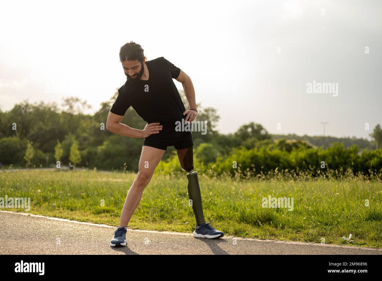 Young man with artificial leg having fitness activity in a public park ...