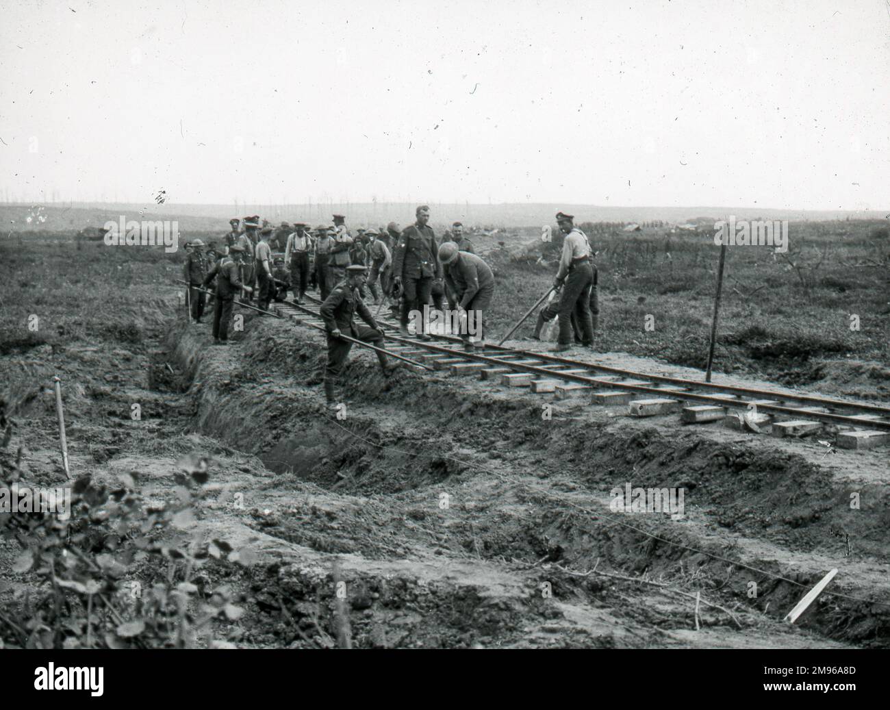 A group of soldiers building a railway track across a battlefield ...