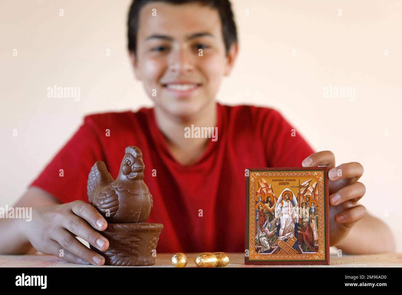 15-year-old boy with an Easter chocolate hen and a christian icon in ...