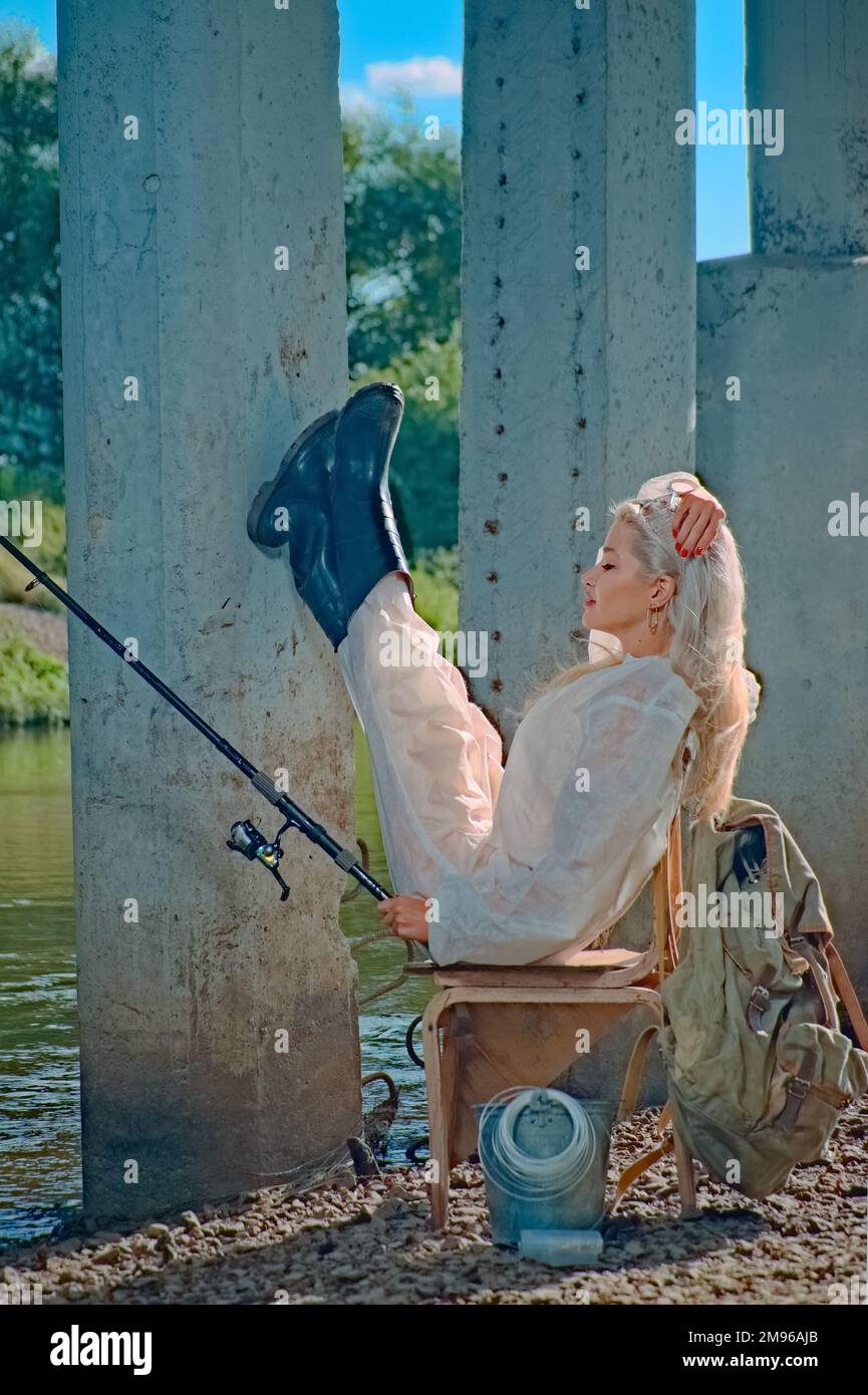 Beautiful woman fisherman is resting on the river. Female is fishing ...