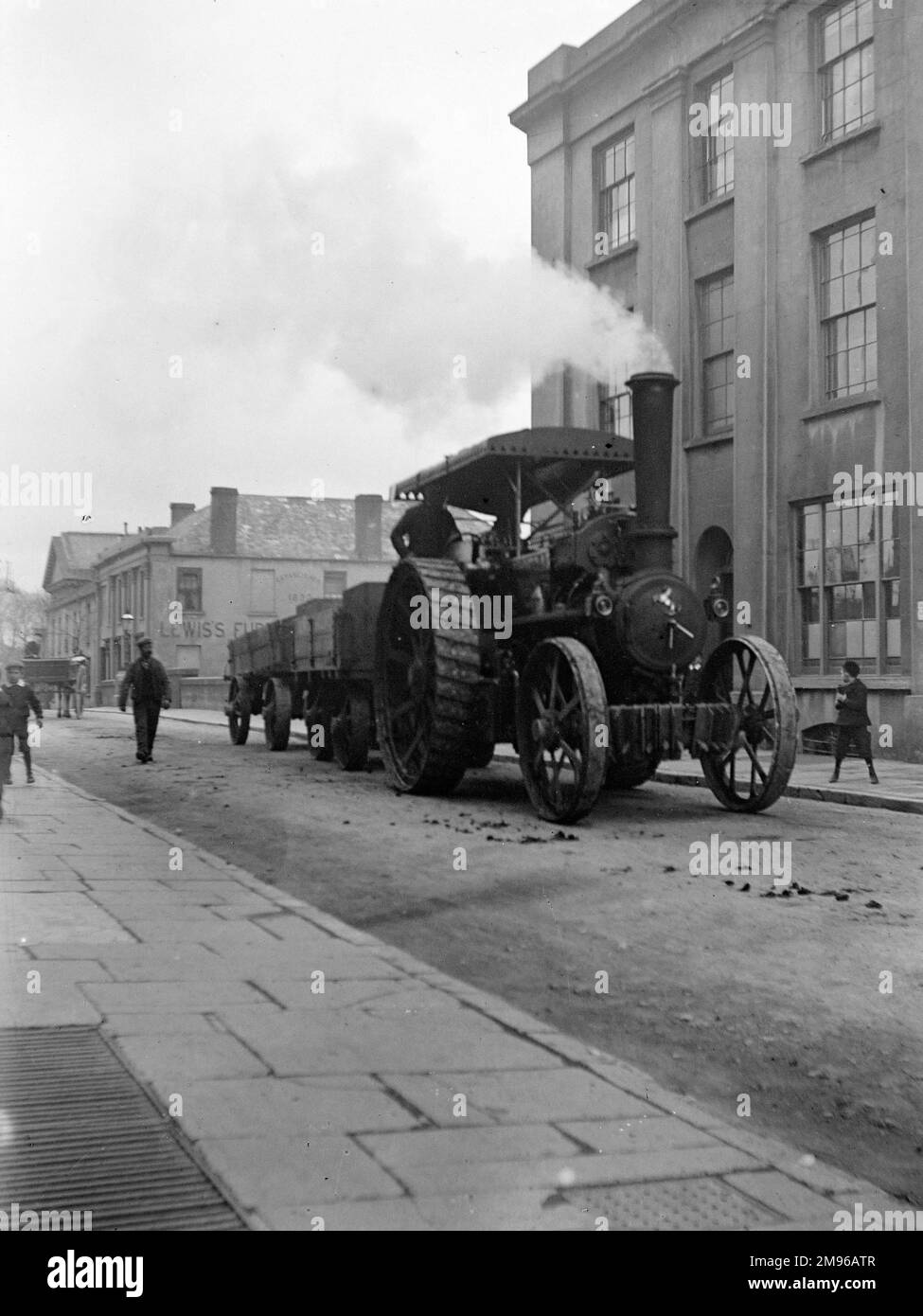 A large traction engine with a smoking funnel transports a load of ...
