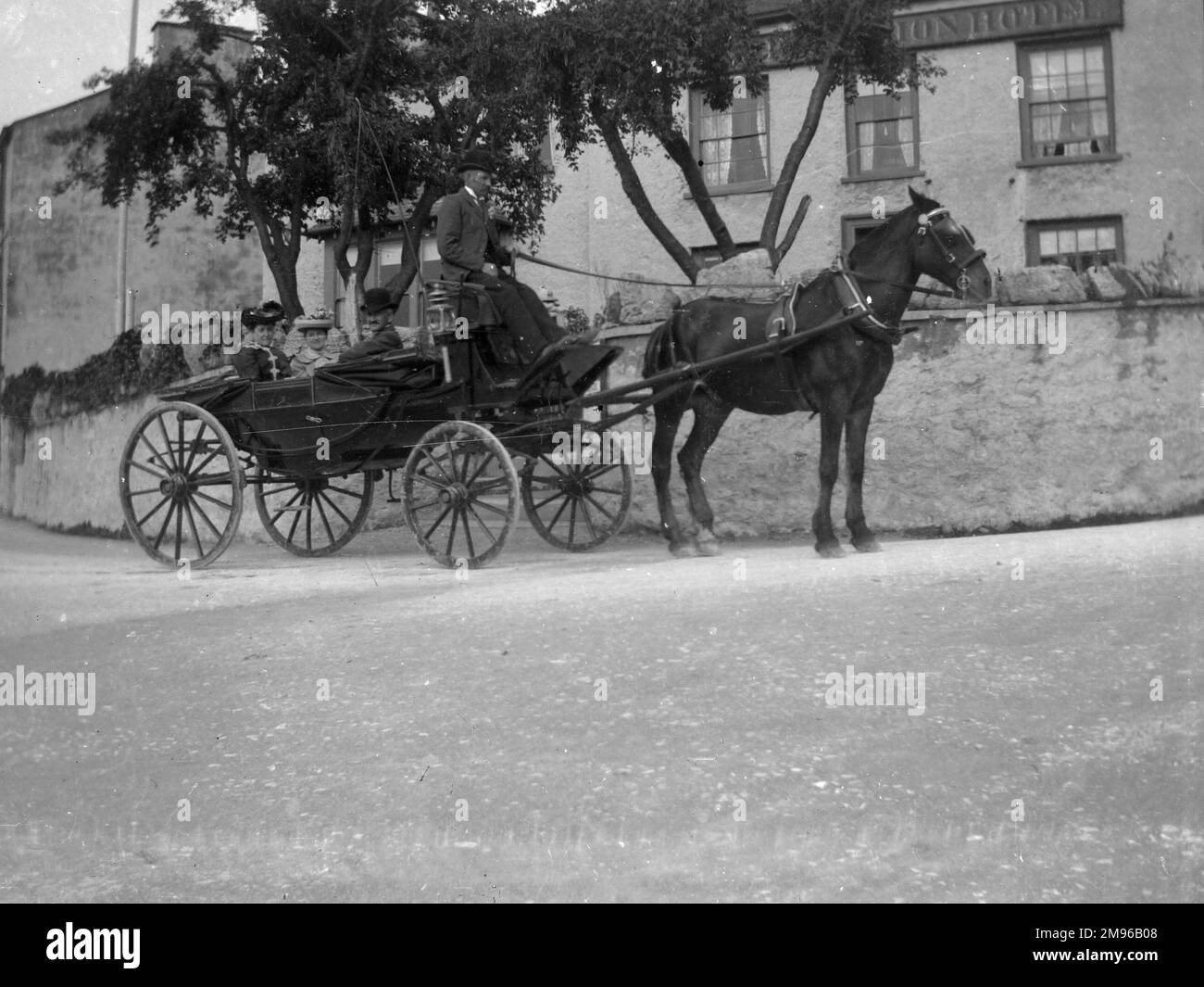 A horse and open carriage with rider and three passengers outside the ...