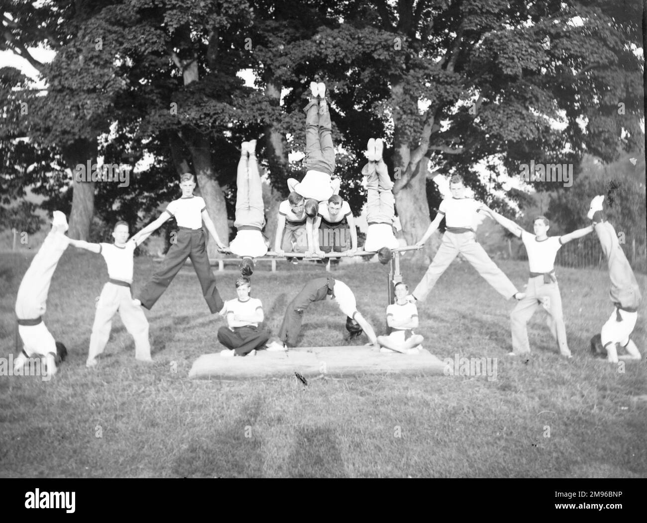 A group of young servicemen doing acrobatics in a field, perhaps as ...