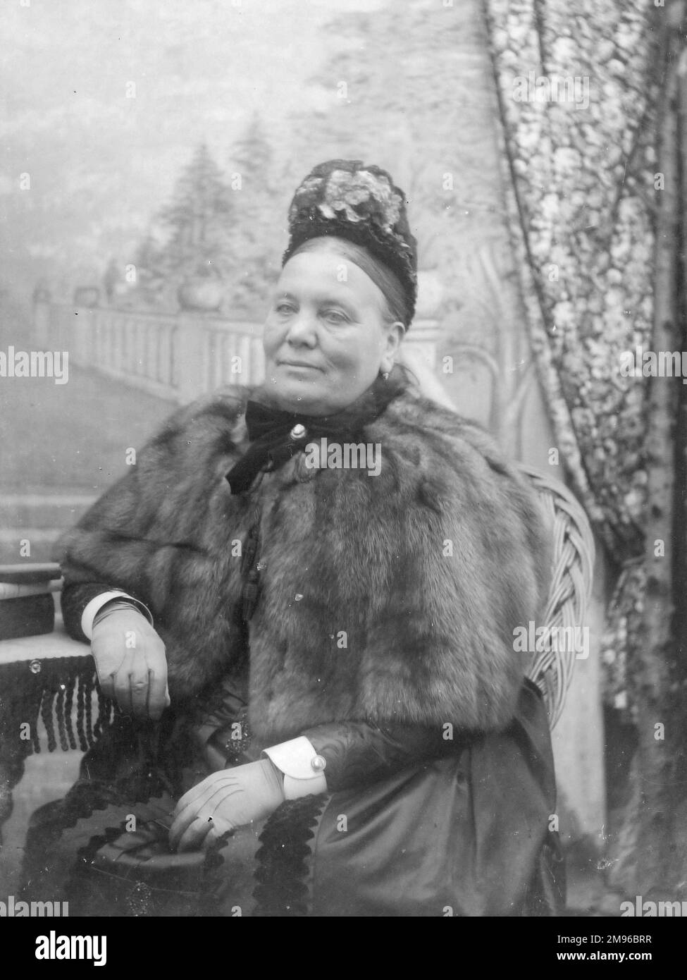 A rather indomitable-looking, plump Edwardian woman in a fur wrap poses ...