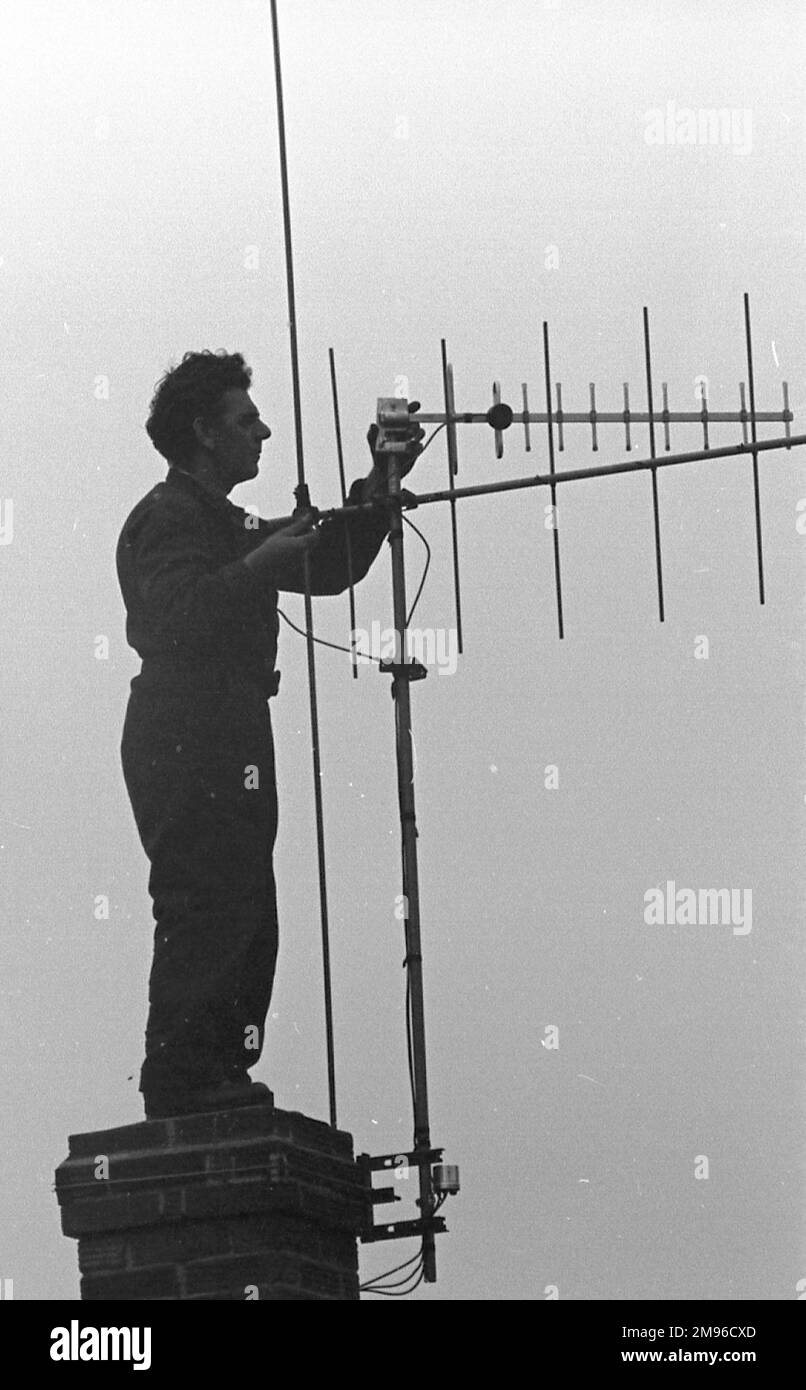 A man stands on top of a chimney to adjust a television aerial Stock ...