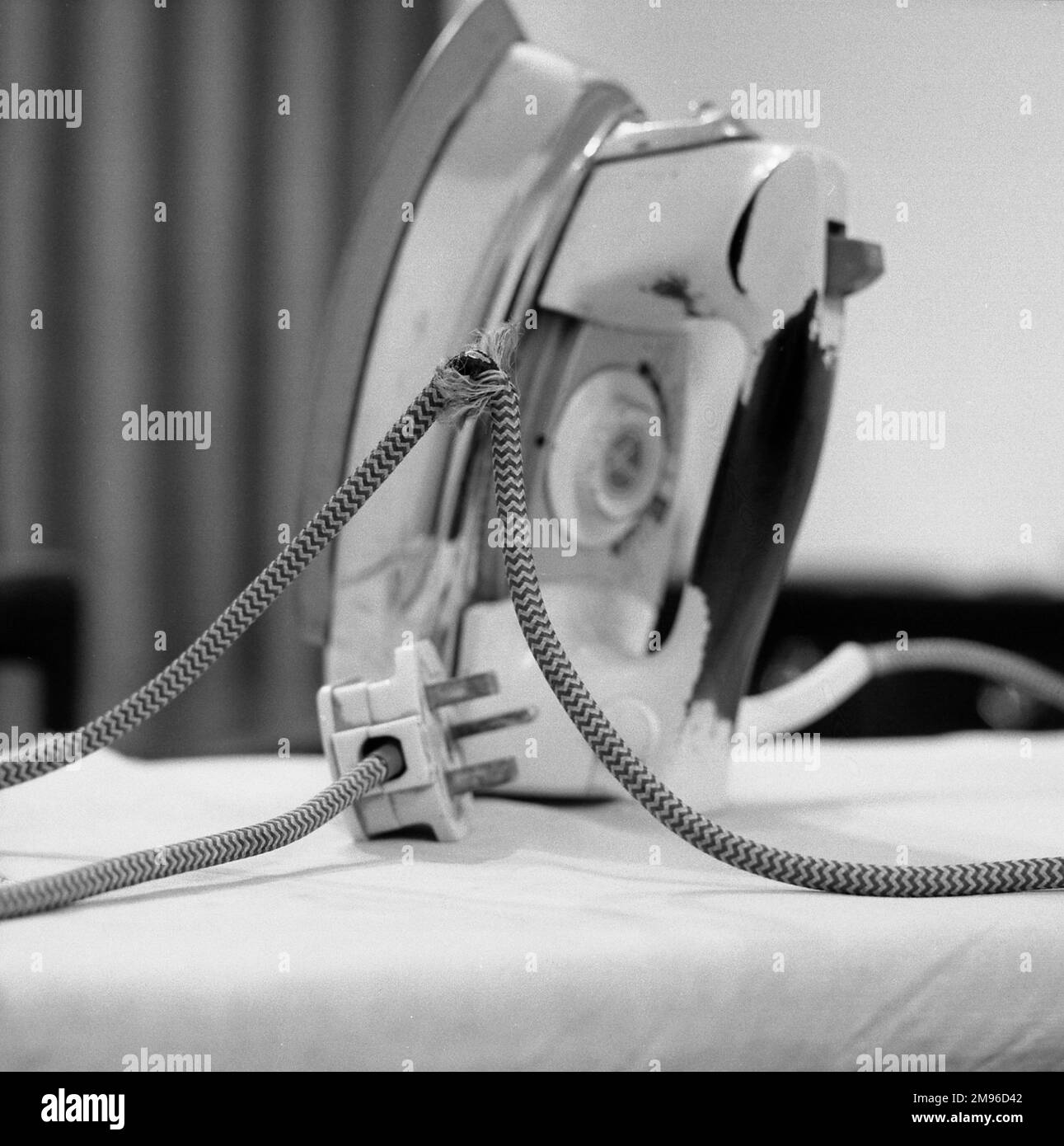 An electric iron with flex and plug, sitting upright on an ironing ...