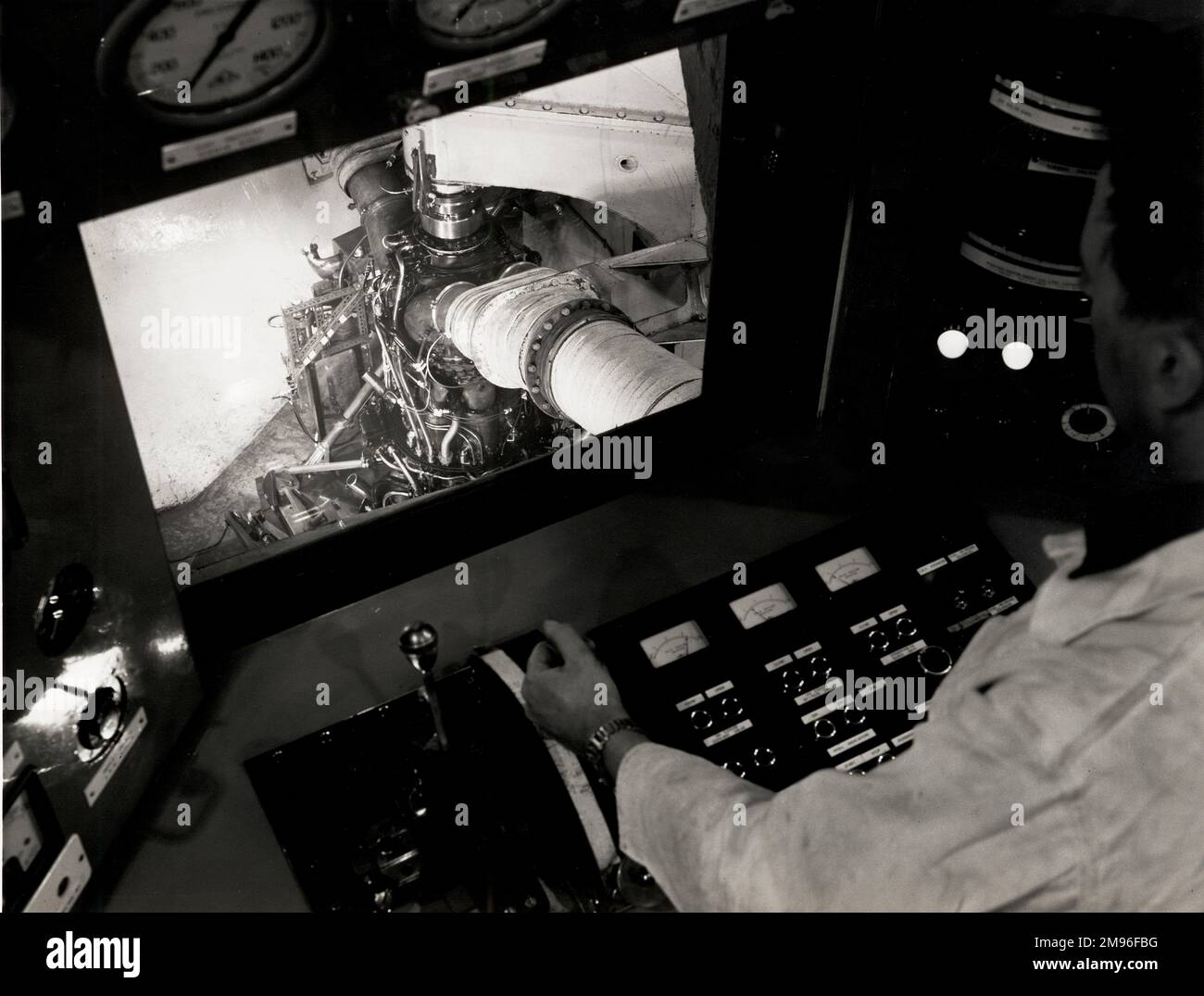 At controls behind a window a technician tests the Gazelle engine Stock ...