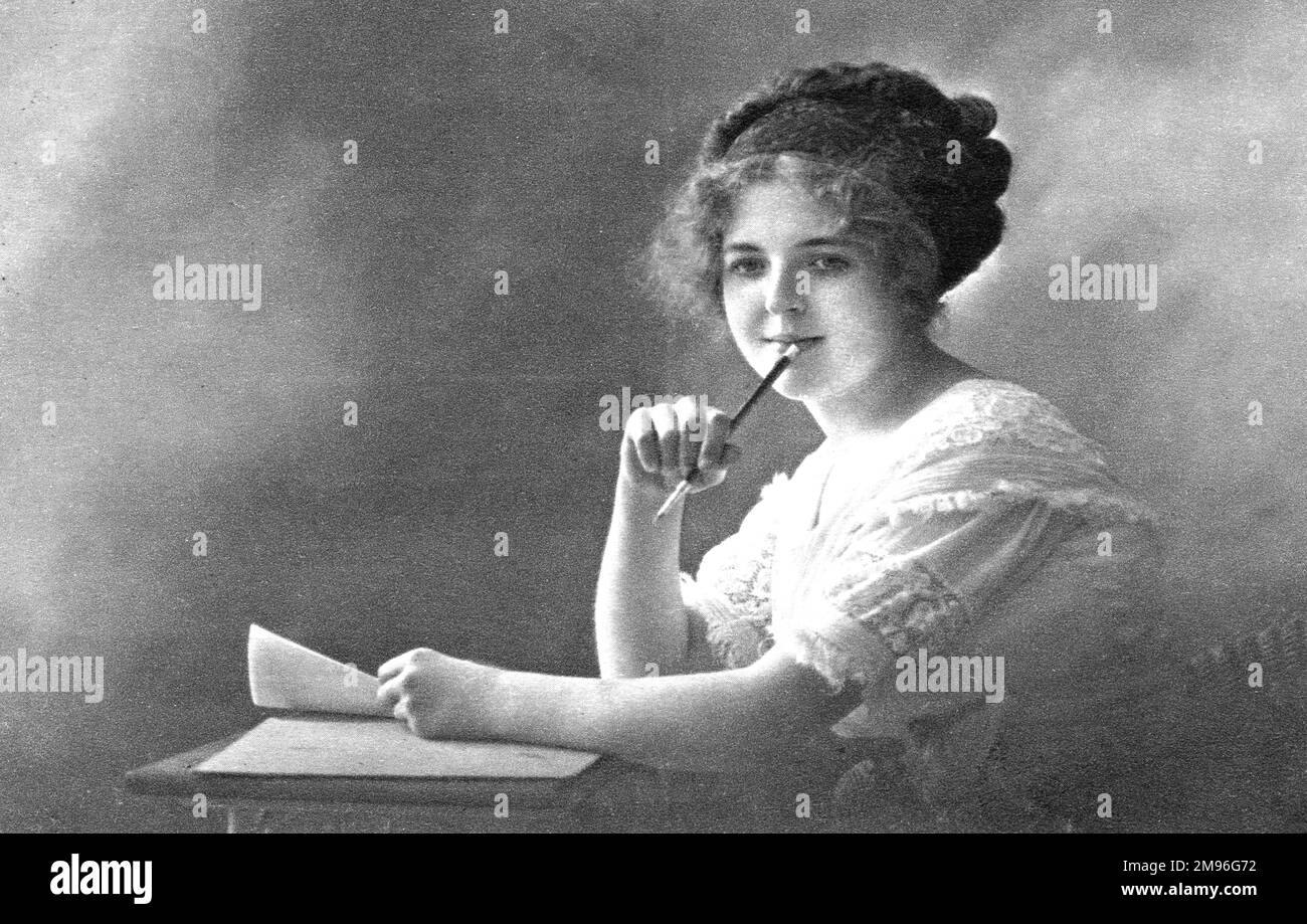 A young woman takes a moment to think about what next to write as she ...