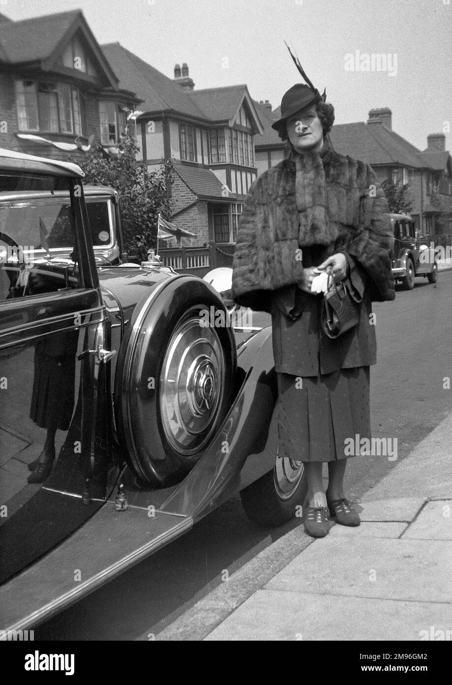 A Middle Class Woman In Smart Clothes Standing By A Shiny Car In A Residential Street Stock