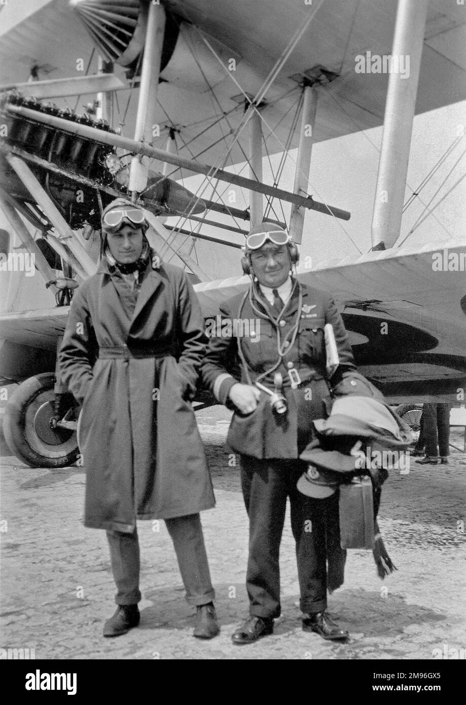 Two airmen in goggles standing in front of a large biplane Stock Photo ...