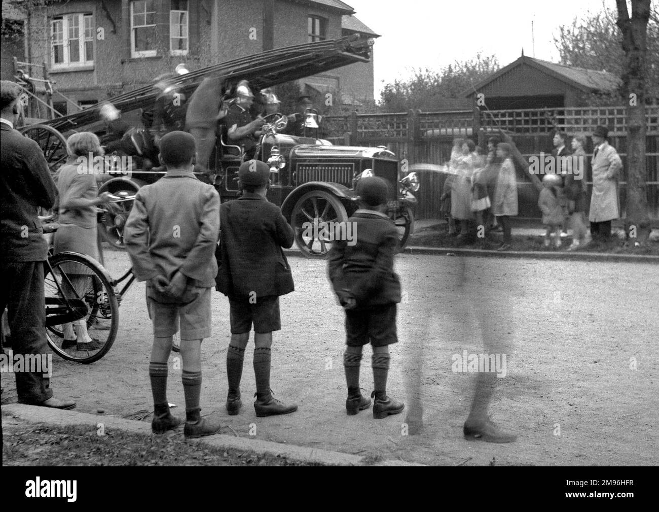 Street scene with people watching a fire engine racing past Stock Photo ...