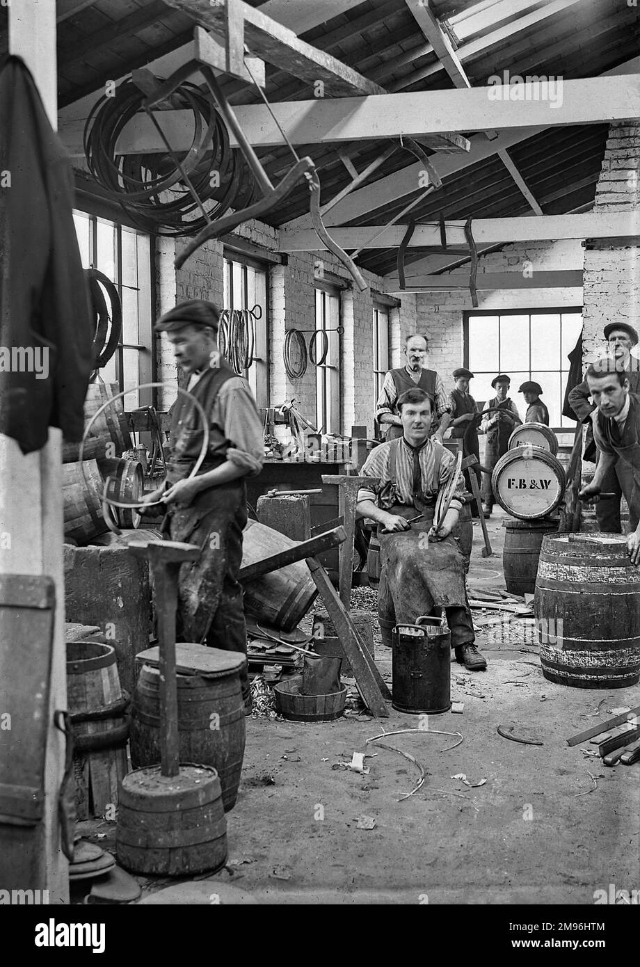 Men and boys in a workshop, most of them looking towards the camera ...
