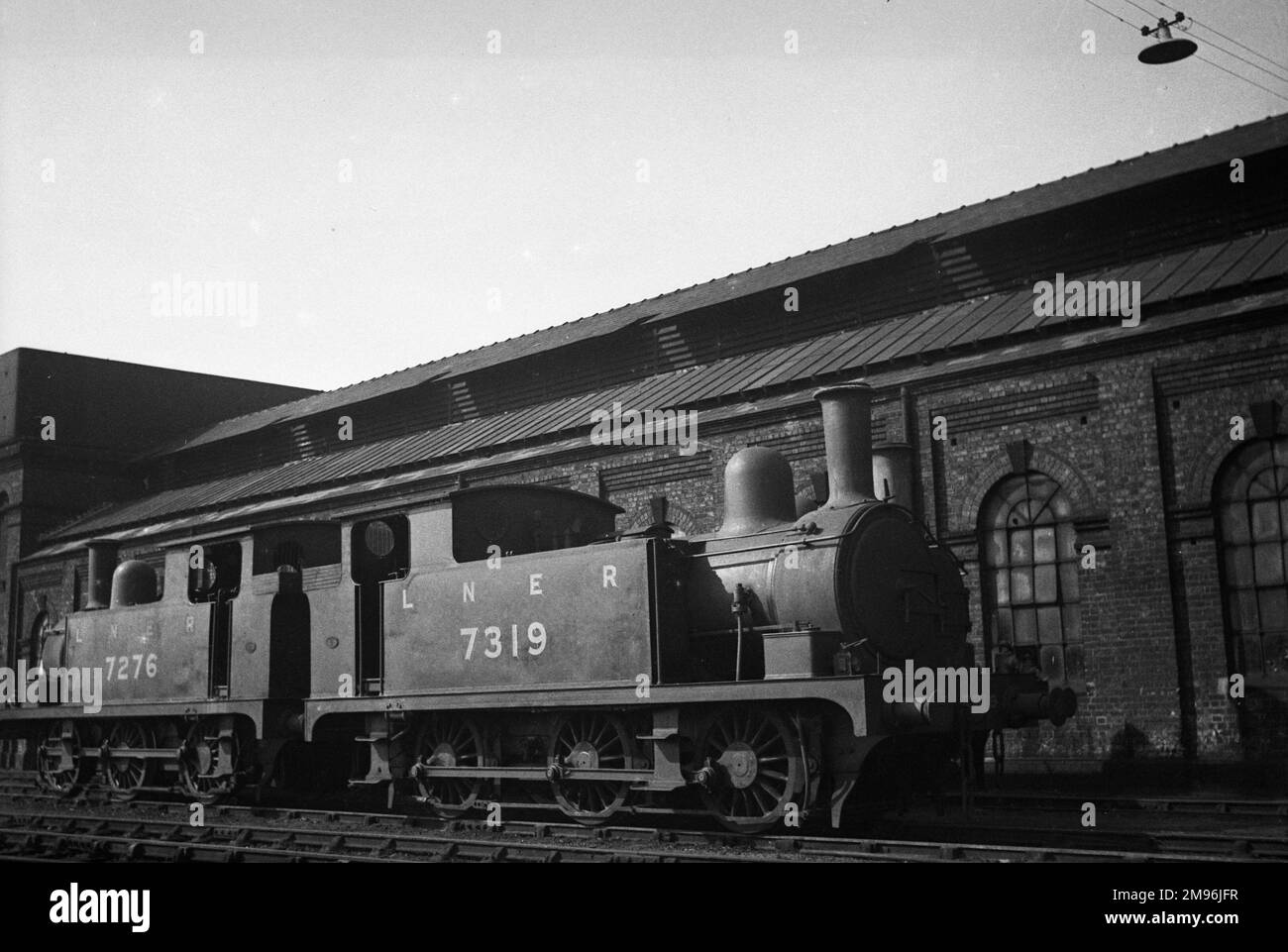 Two LNER (London & North Eastern) steam engines on a railway track alongside a building Stock ...
