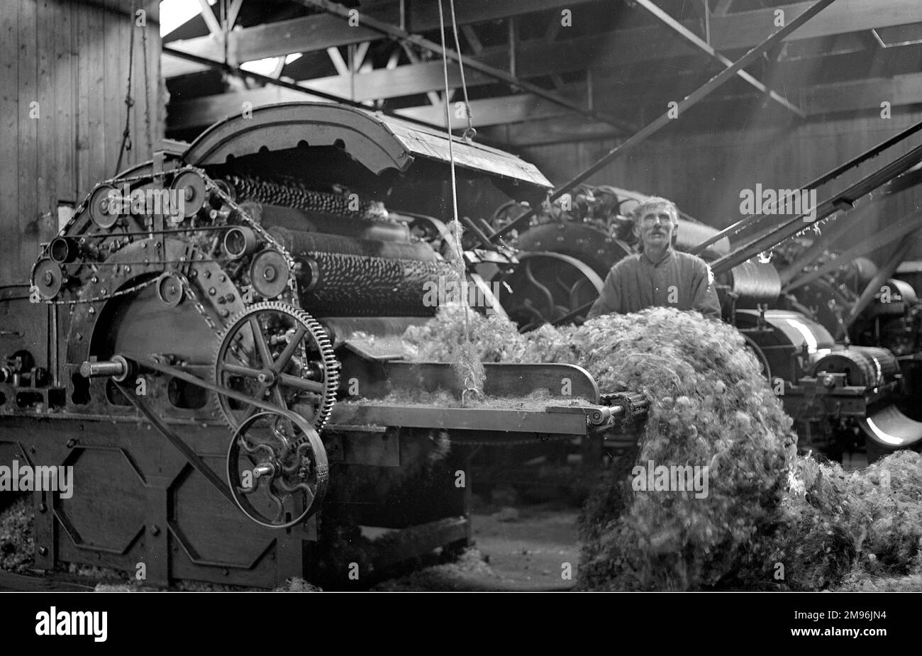 A man in the textile industry in Scotland, operating a machine with ...