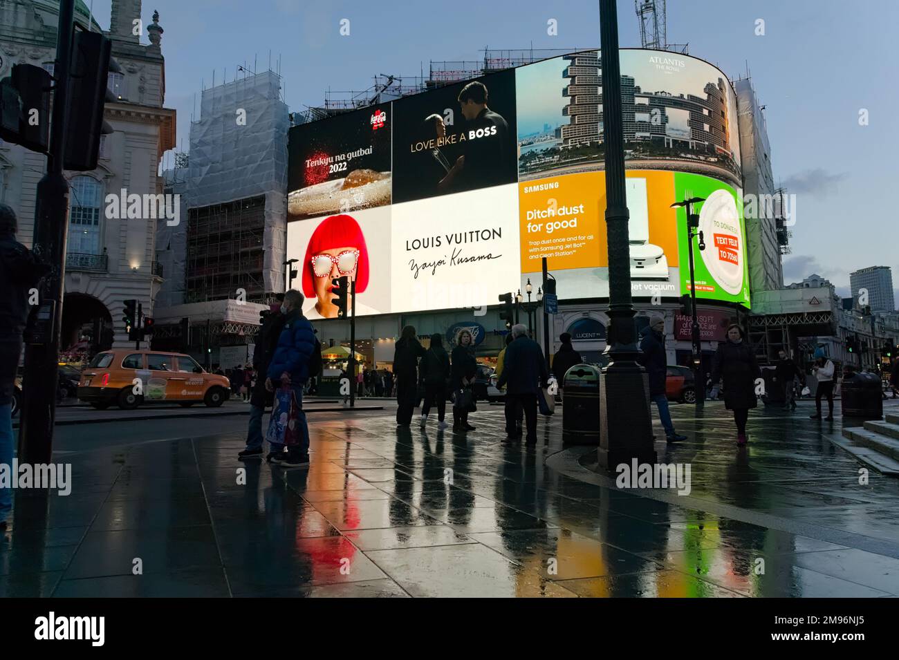 People walking on the wet pavement with the famous advertising signs in ...
