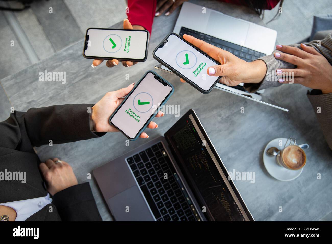Overhead shot of three businesswomen paying bill at a bar with smart ...