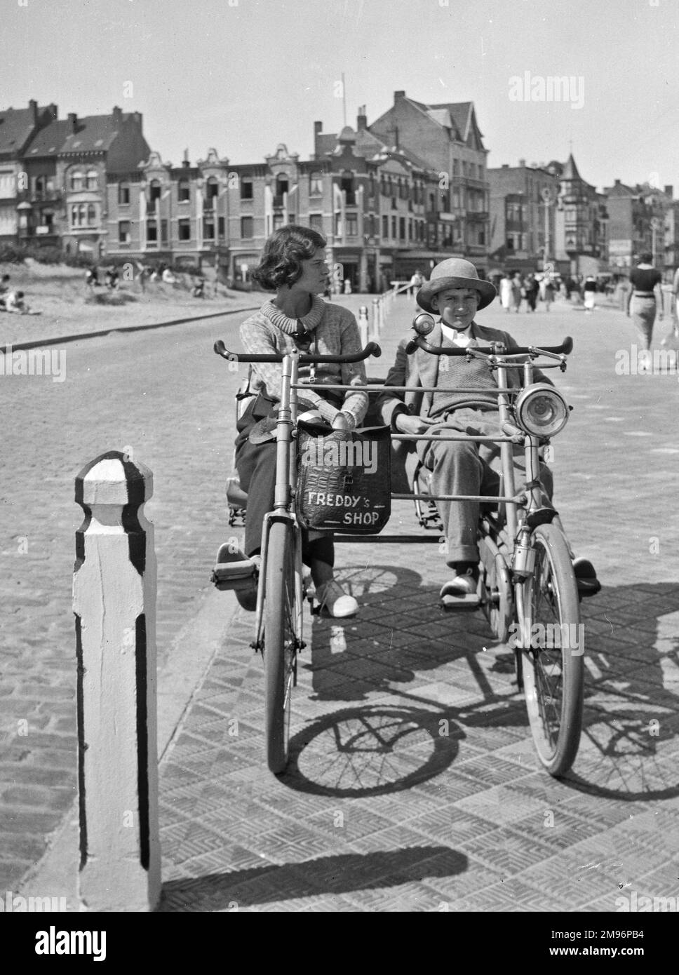 A young woman and a boy riding a four-wheeled two-seater cycle (also ...