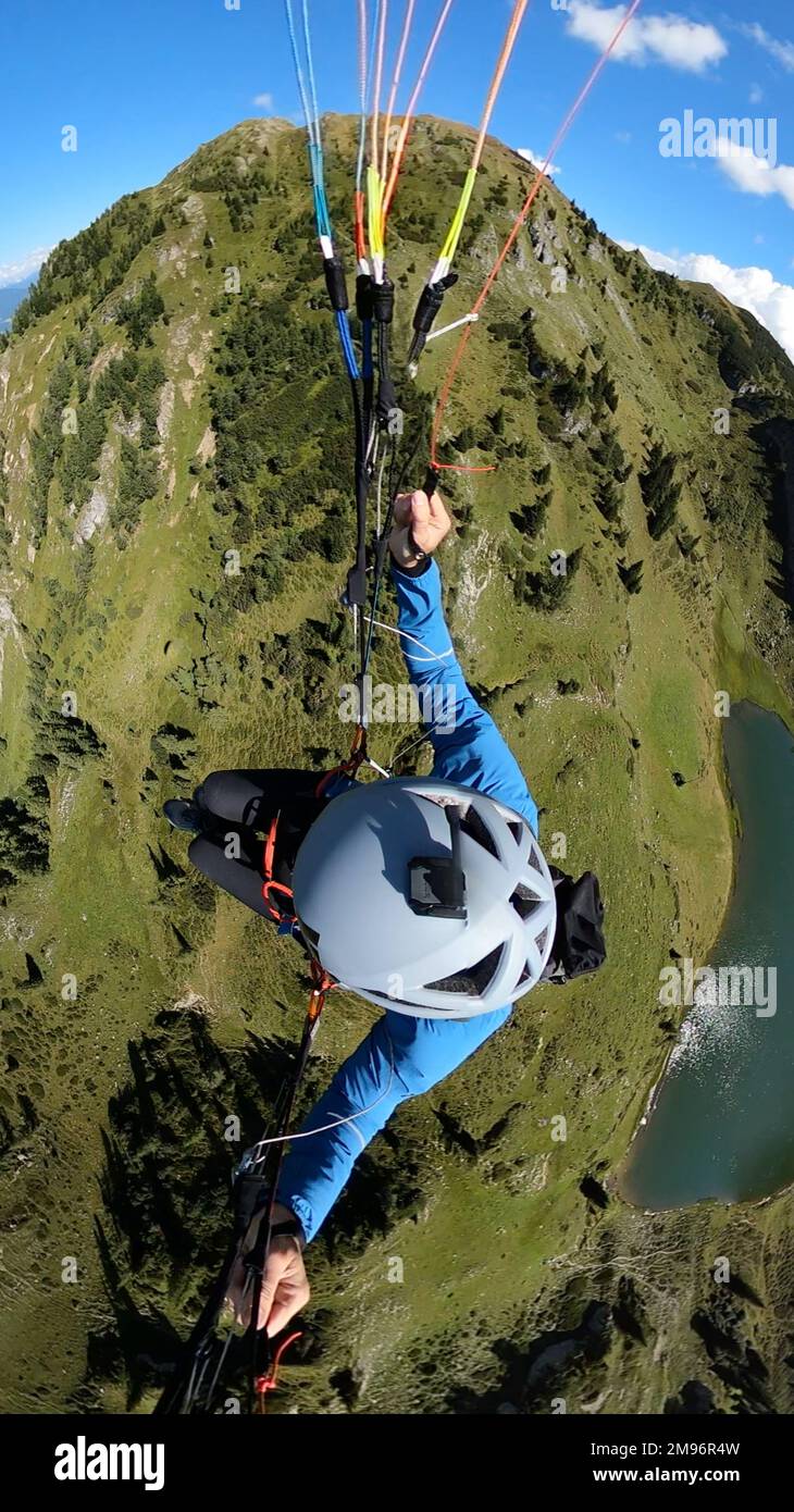 A vertical top view of a skydiver paragliding on a scenic landscape ...