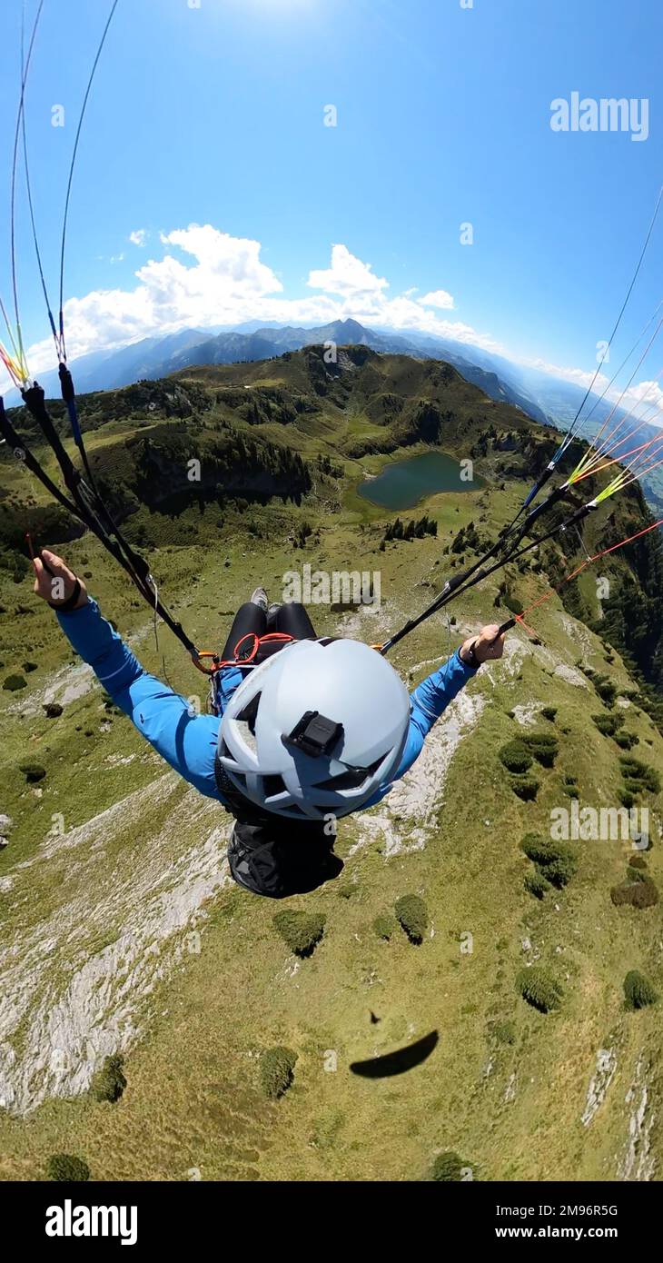 A vertical top view of a skydiver paragliding on a scenic landscape ...