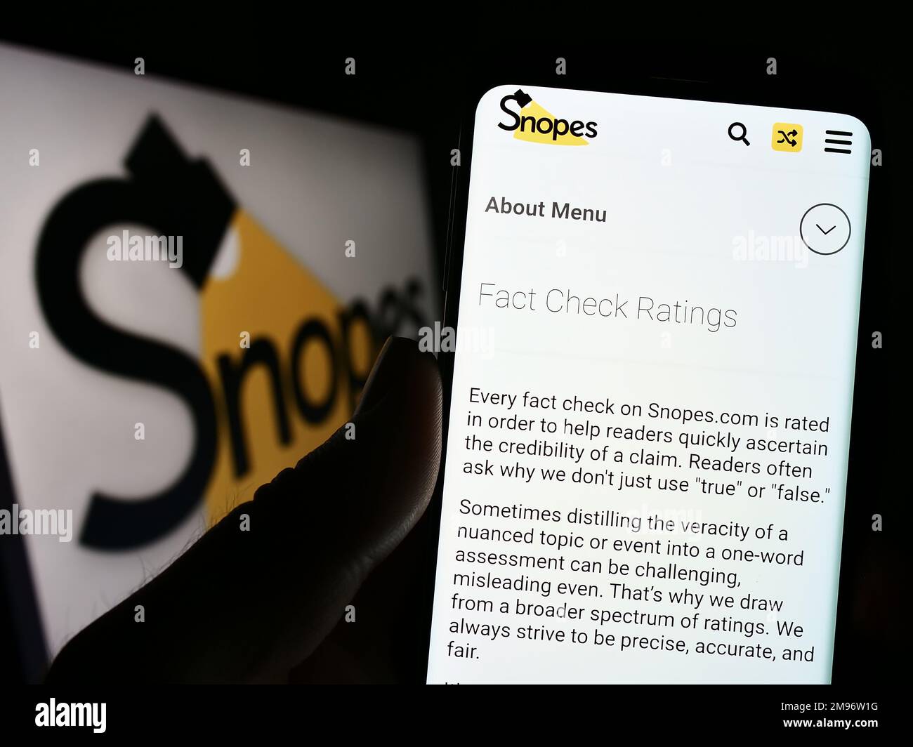 Person holding mobile phone with webpage of fact checking platform ...