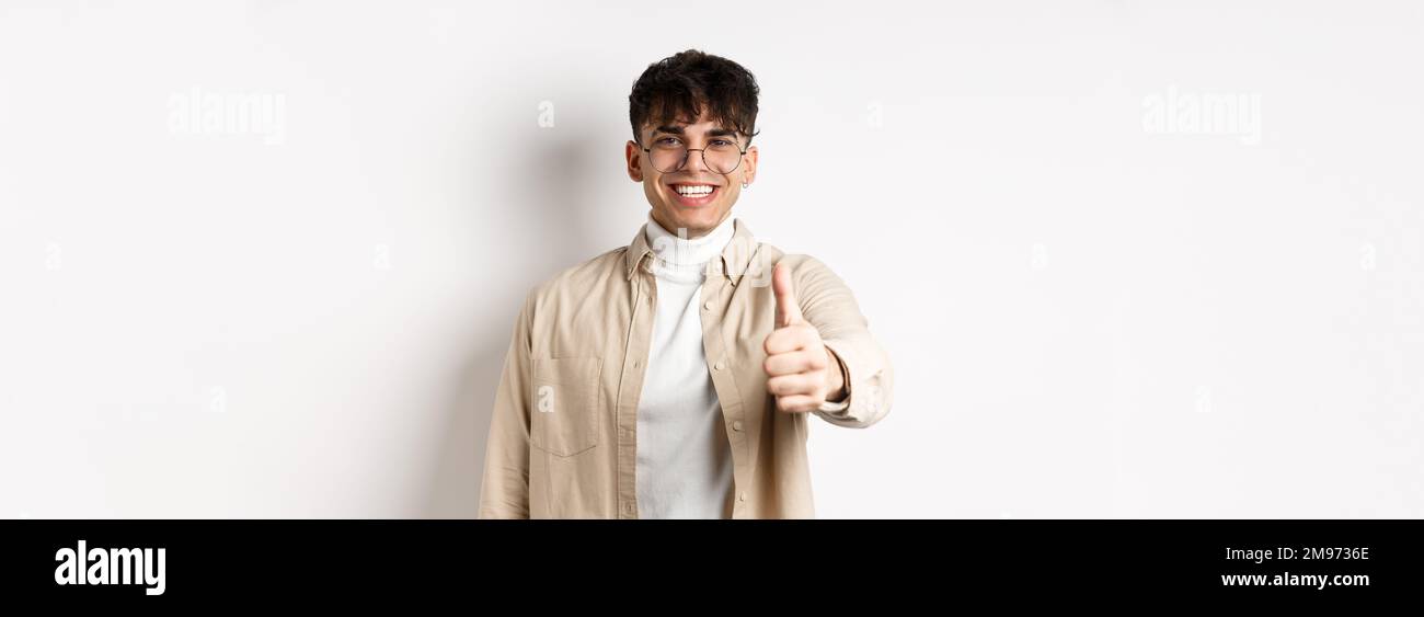 Image of happy young man showing thumb up and smiling satisfied, praise ...