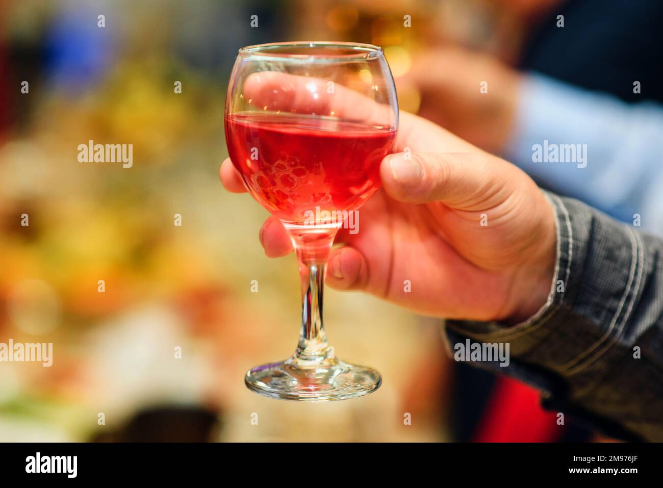 hand of a man with a glass of red wine closeup with blurred background ...