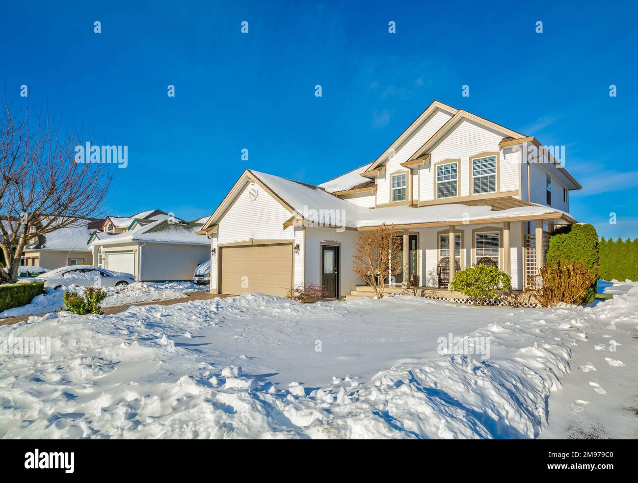 Family house with driveway and front yard in snow on winter sunny day ...