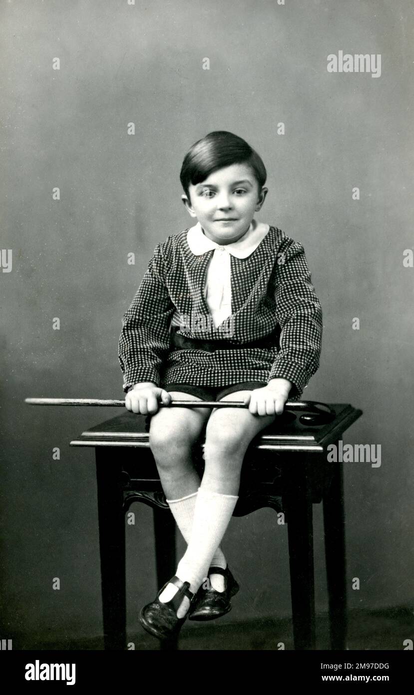 Little boy sitting on a stool, cane in hand, poses for the camera Stock ...
