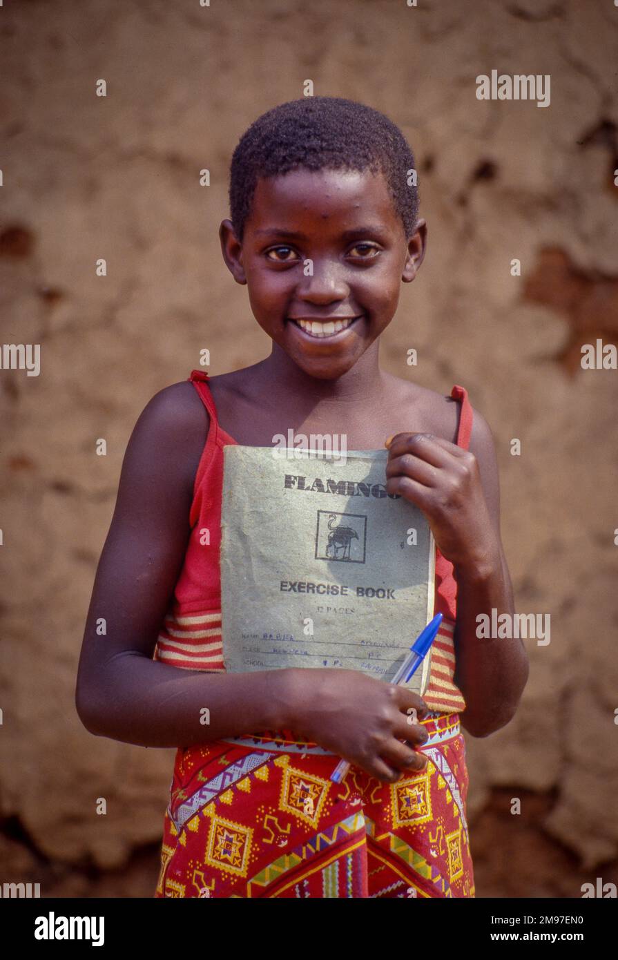 Uganda, Mbarara; girl with exercise book in front of her, adobe made ...