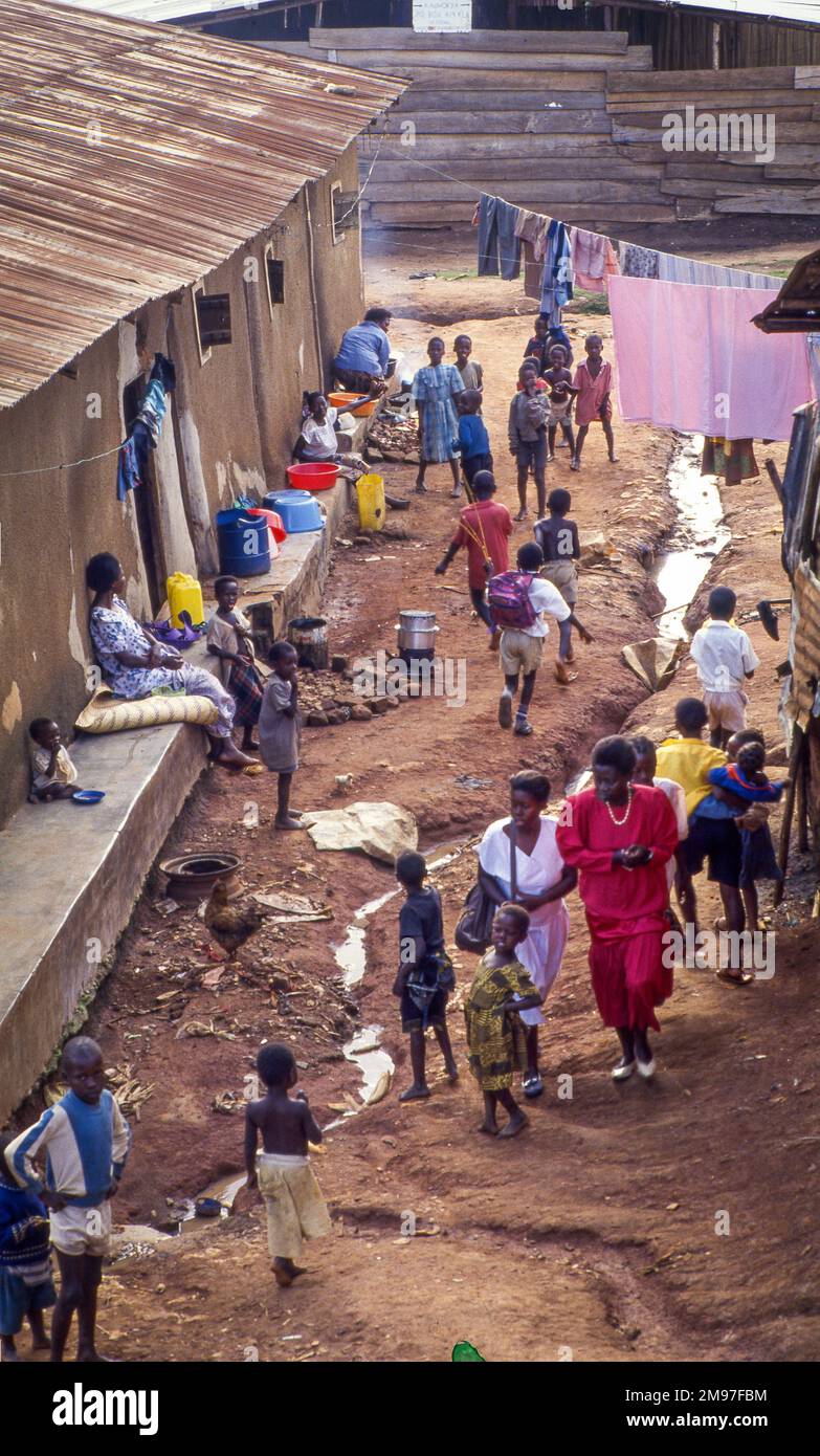 Uganda, people walking along an open sewer in a poor neighborhood of ...