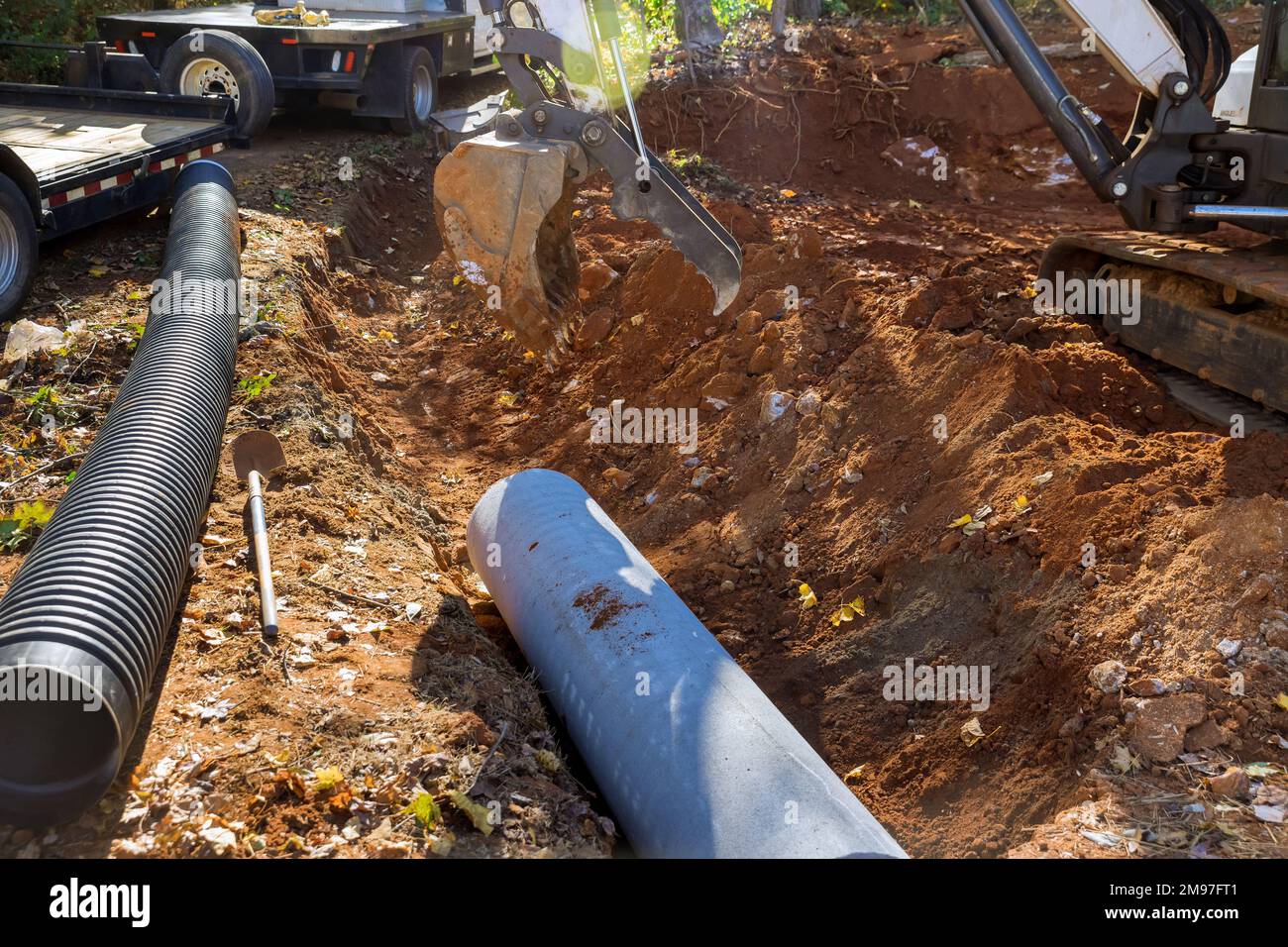 Worker operating tractor lift sewage pipes in ground is preparing to ...