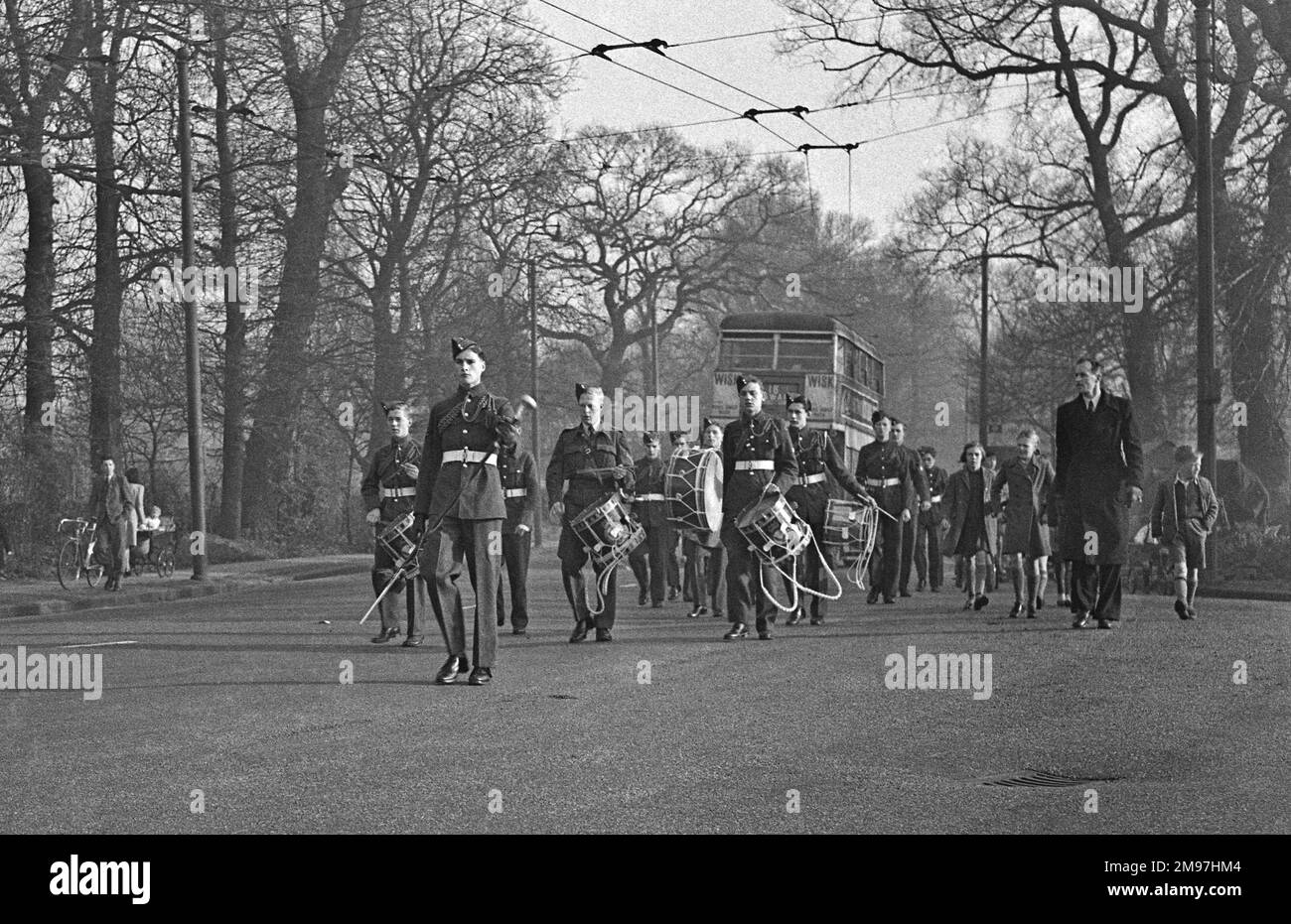 Band of musicians marching along a road, with a double decker bus ...