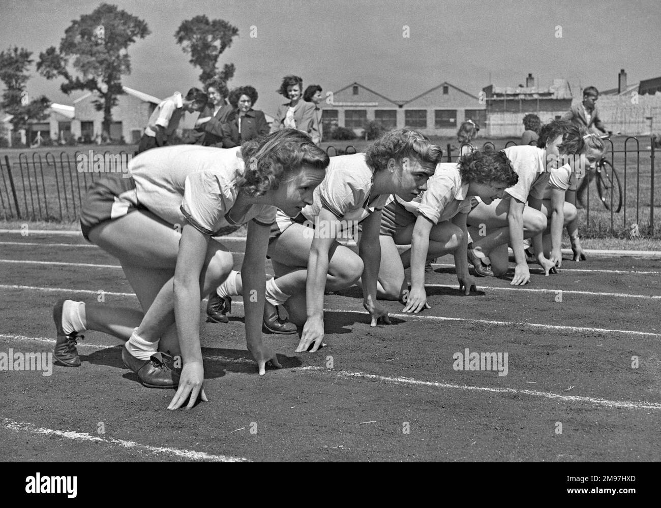 Five women athletes on the starting line at a sports track, with ...