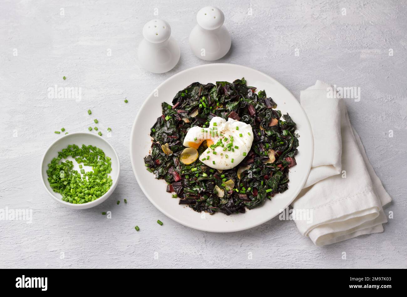 Braised chard with garlic and poached egg, seasoned with spices and ...