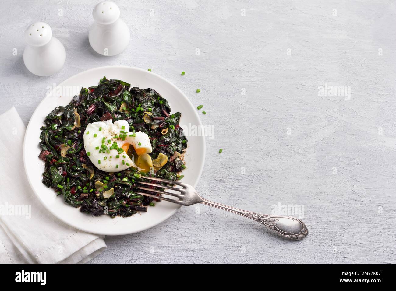 Braised chard with garlic and poached egg, seasoned with spices and ...