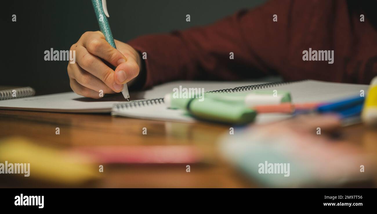 Low angle closeup view of a child making homework, writing in his ...