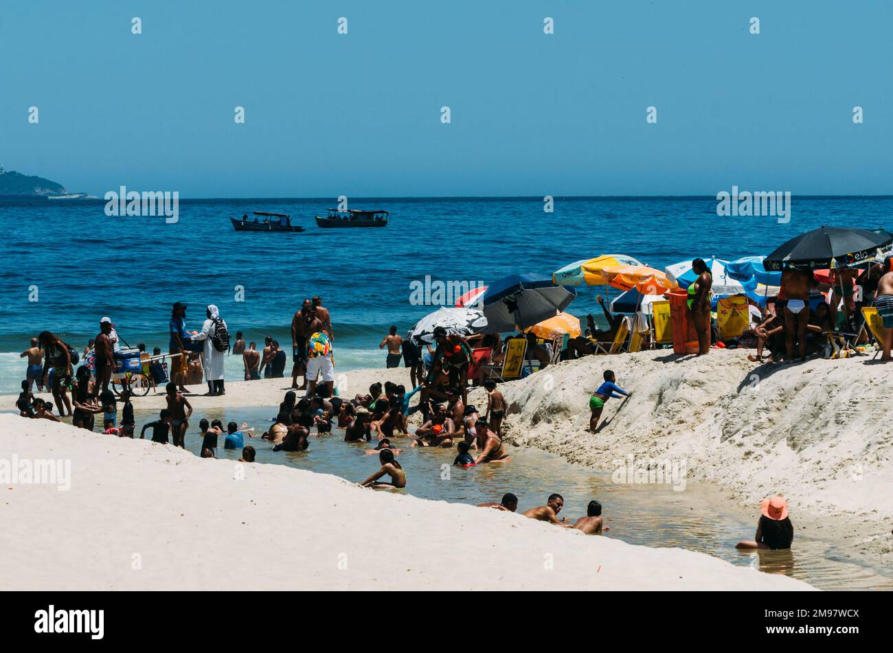 People enjoy playing next to the water at a crowded Copacabana Beach in ...